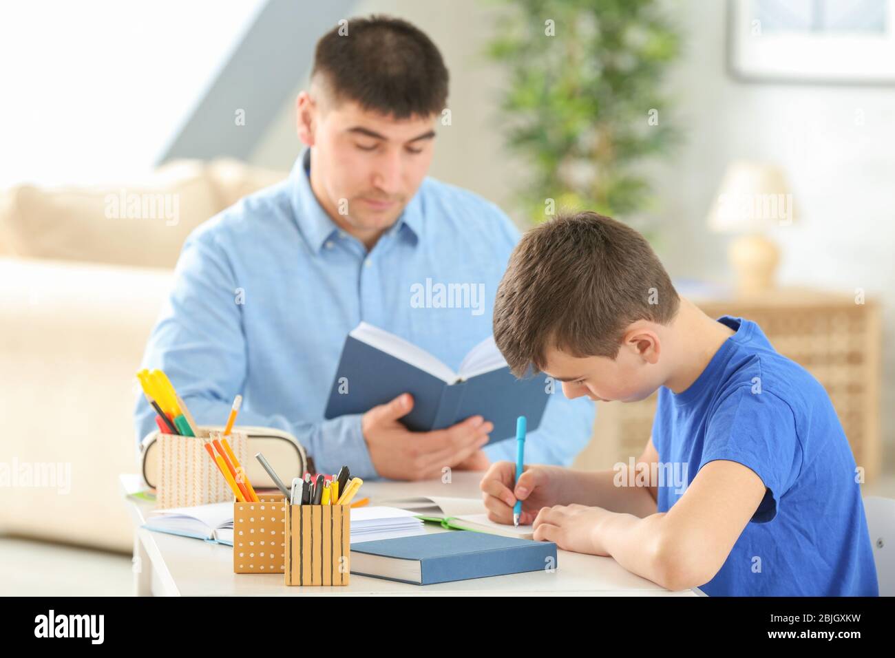 Father and son doing homework together indoors Stock Photo - Alamy
