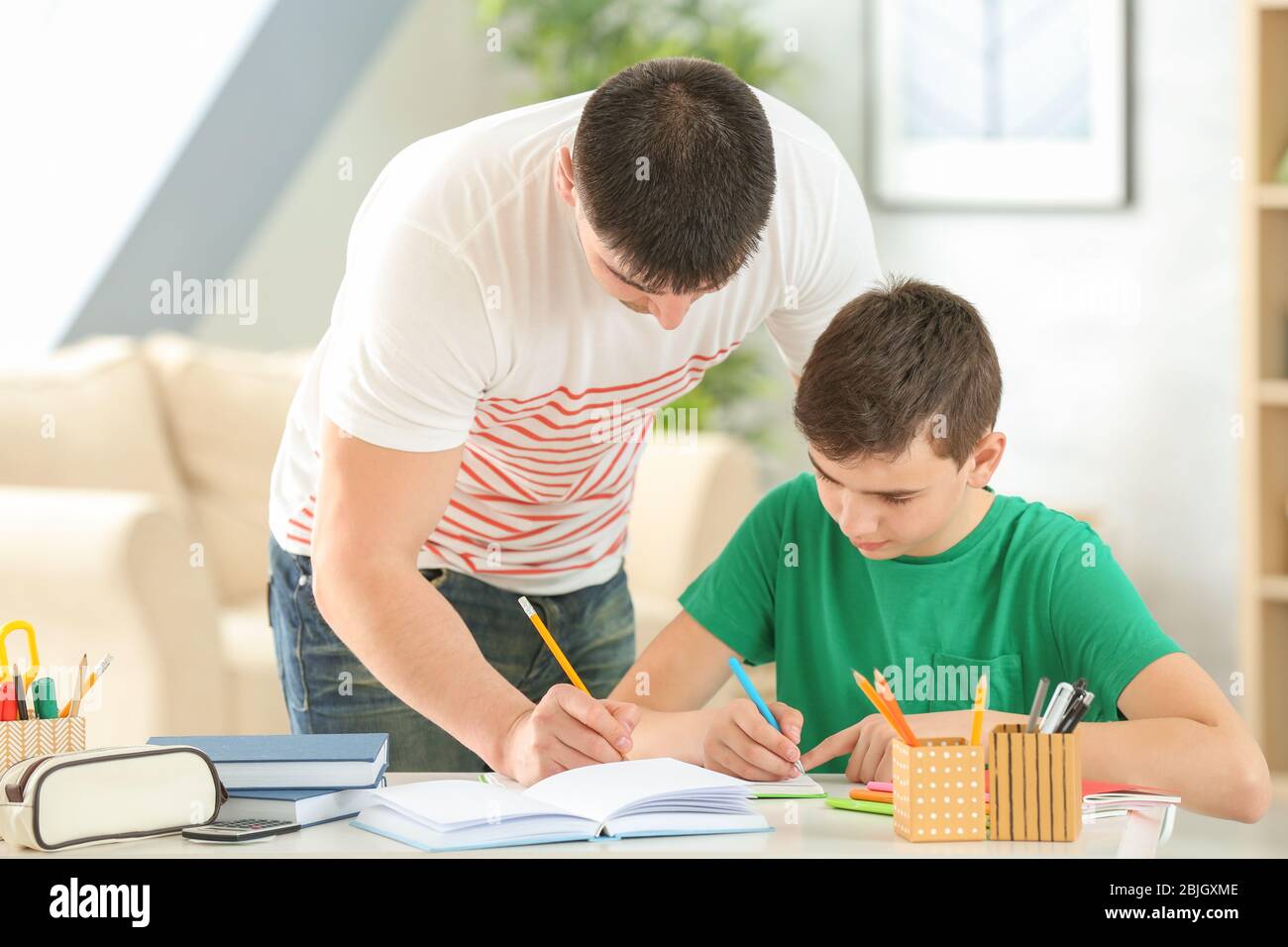 Father and son doing homework together indoors Stock Photo - Alamy