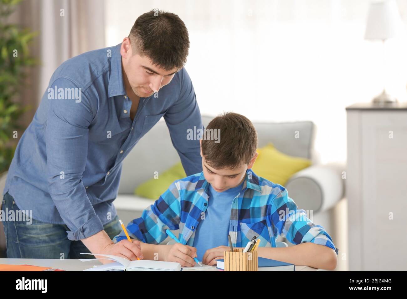 Father and son doing homework together indoors Stock Photo - Alamy