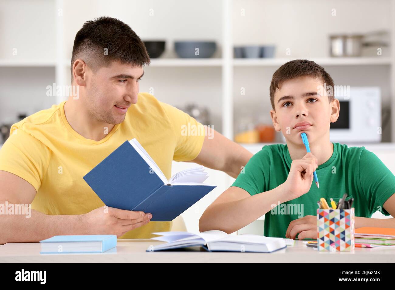 Father and son doing homework together indoors Stock Photo - Alamy