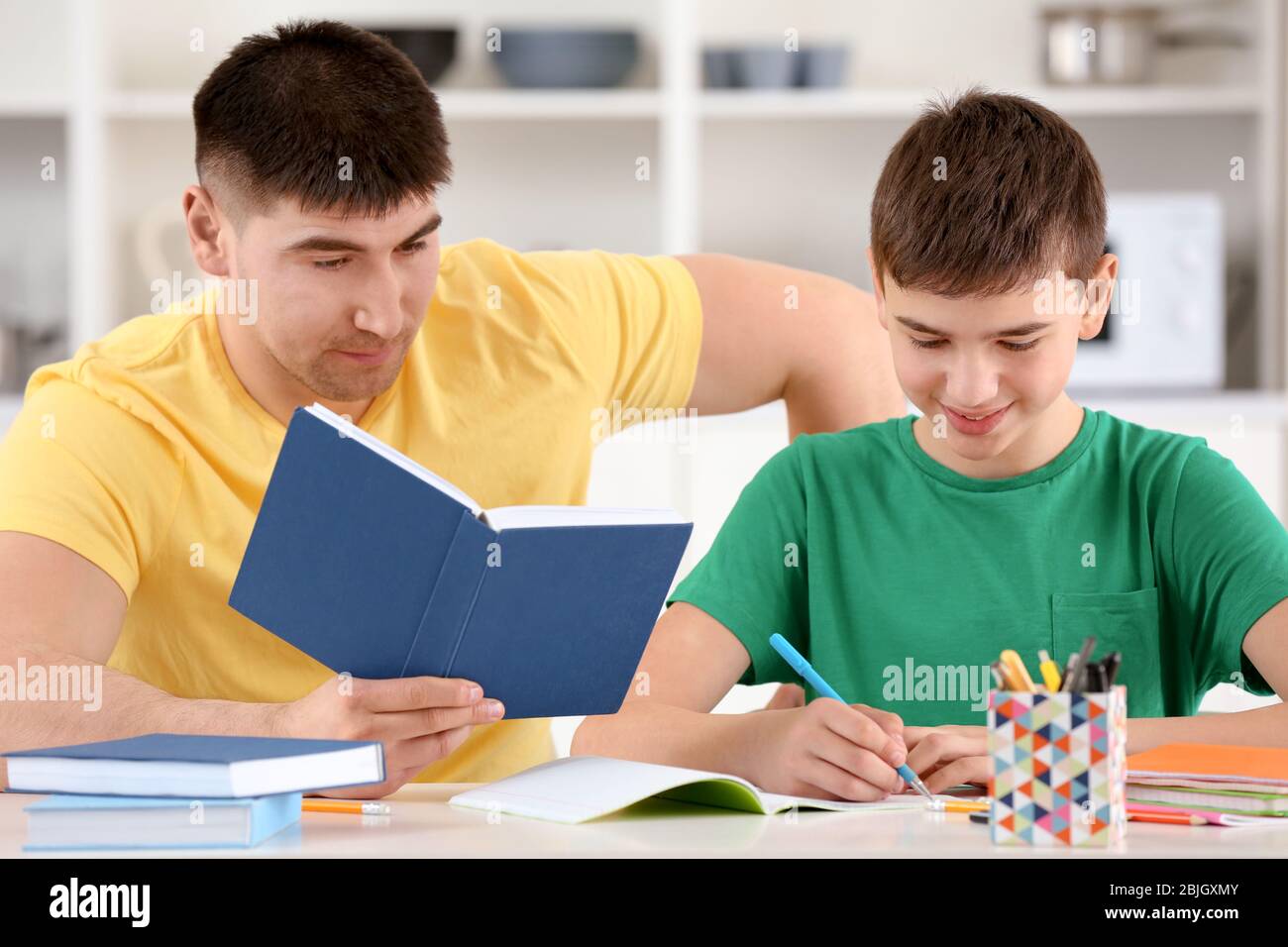 Father and son doing homework together indoors Stock Photo - Alamy