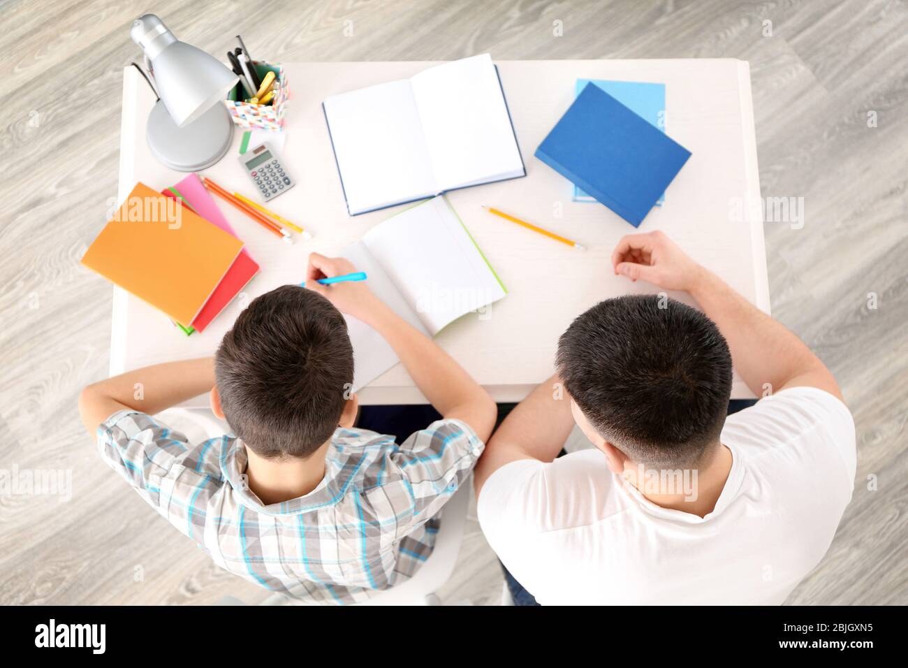 Father and son doing homework together indoors Stock Photo - Alamy