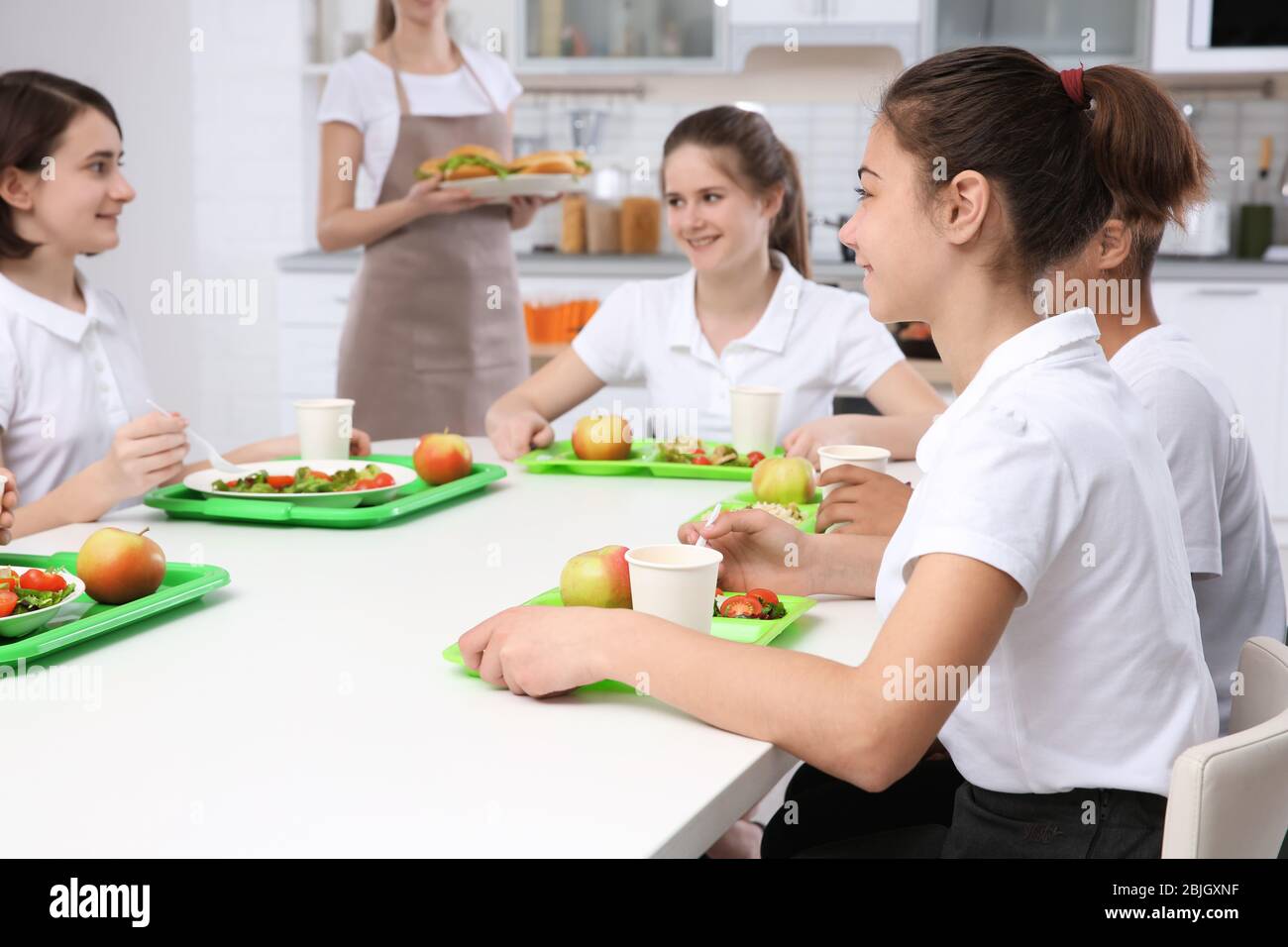 Children sitting at table in school cafeteria while eating lunch Stock ...
