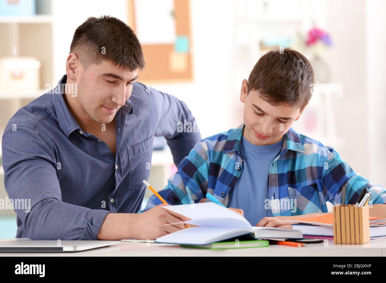 Father and son doing homework together indoors Stock Photo - Alamy