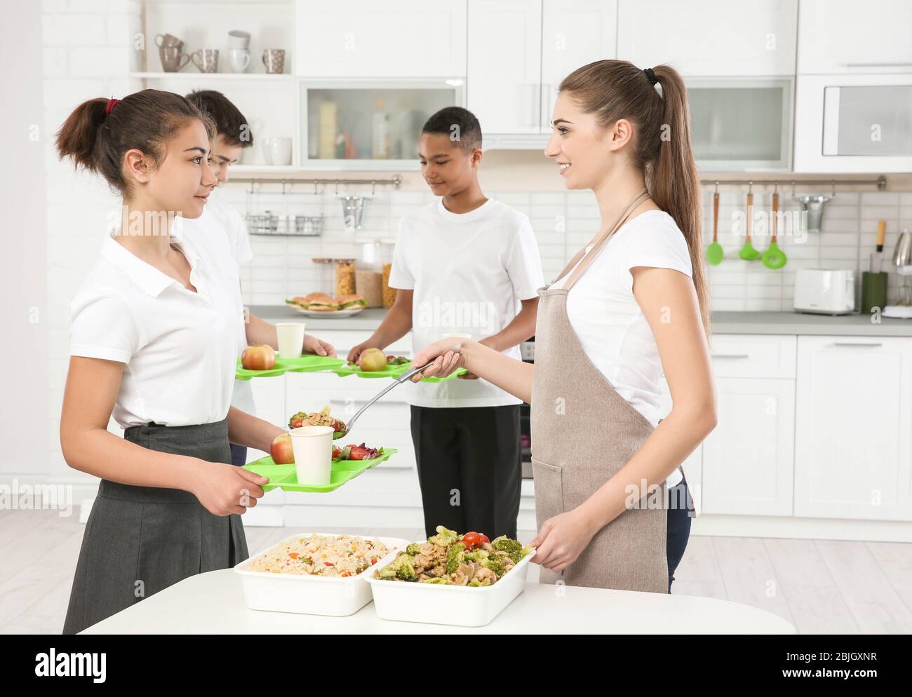 Young woman serving lunch to school girl at canteen Stock Photo - Alamy