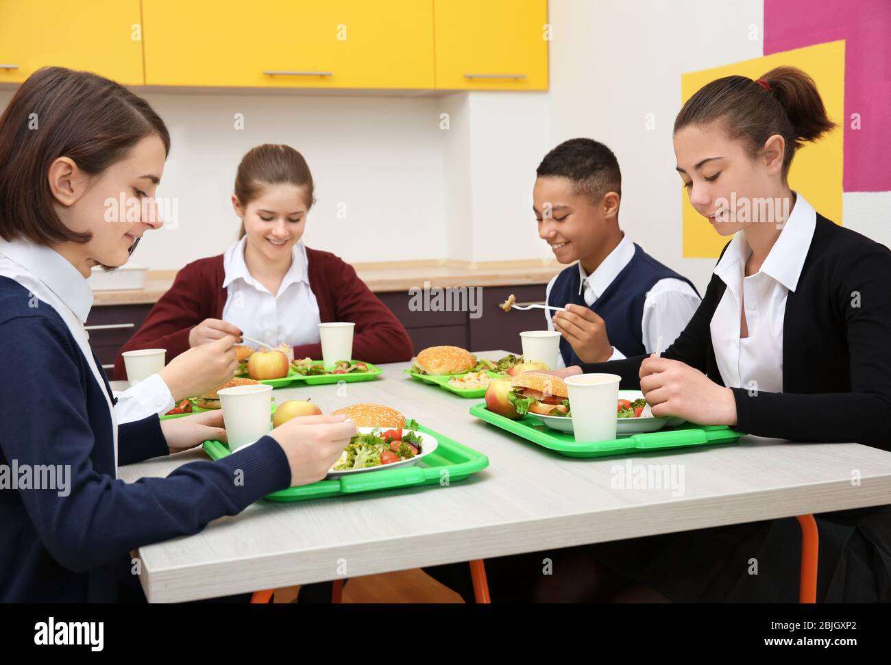 Children sitting at table in school cafeteria while eating lunch Stock ...