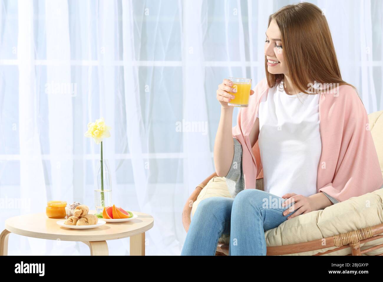 Young beautiful woman having breakfast in armchair Stock Photo - Alamy