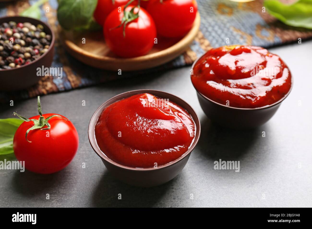 Delicious ketchup in bowls with ingredients on dark background Stock ...