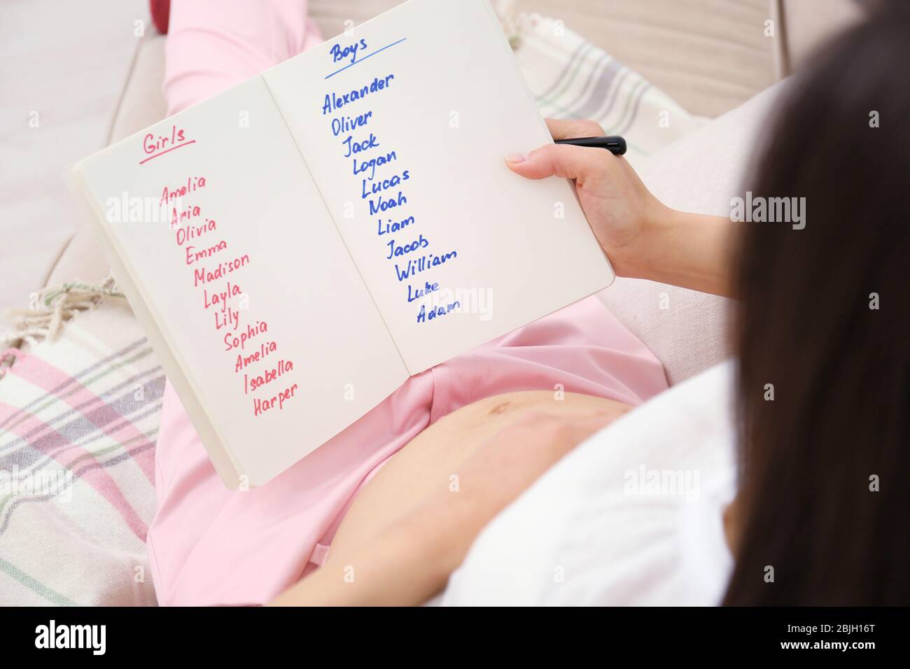 Pregnant woman studying list of names at home. Concept of choosing baby ...