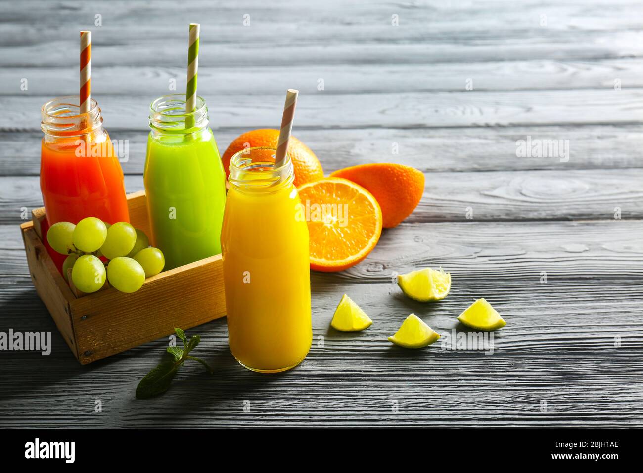 Bottles of delicious juice with ingredients on wooden background Stock ...