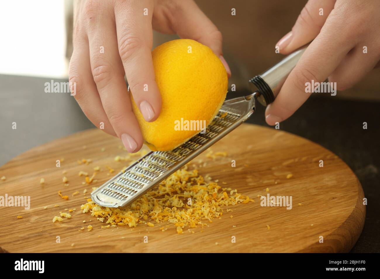 Woman grating zest of lemon on kitchen table Stock Photo - Alamy