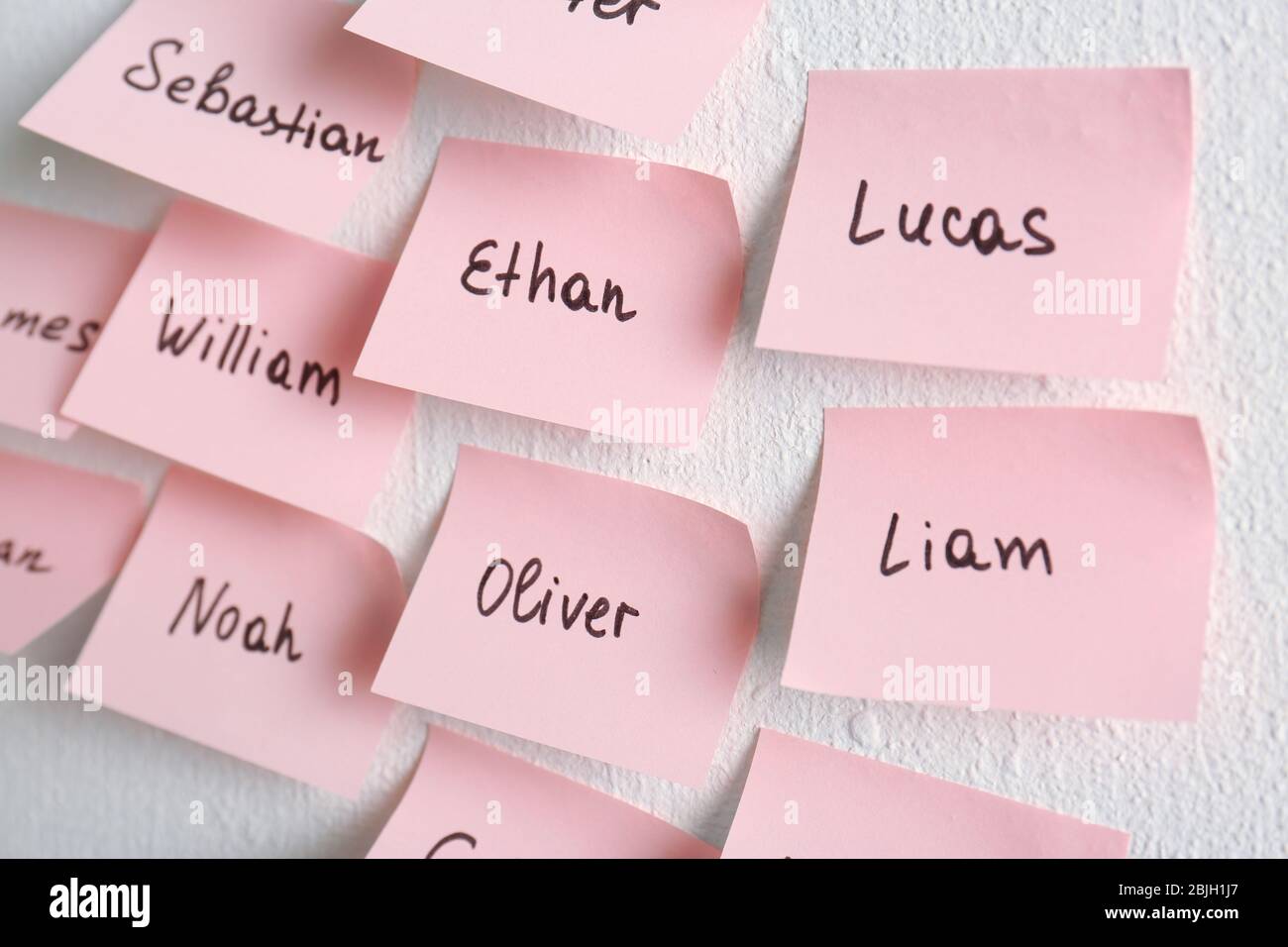 Paper stickers with different names on light textured wall Stock Photo ...