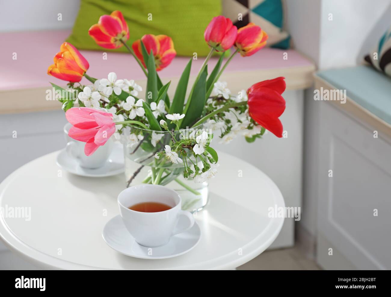 Vase with beautiful flowers and tea set on table in modern veranda ...