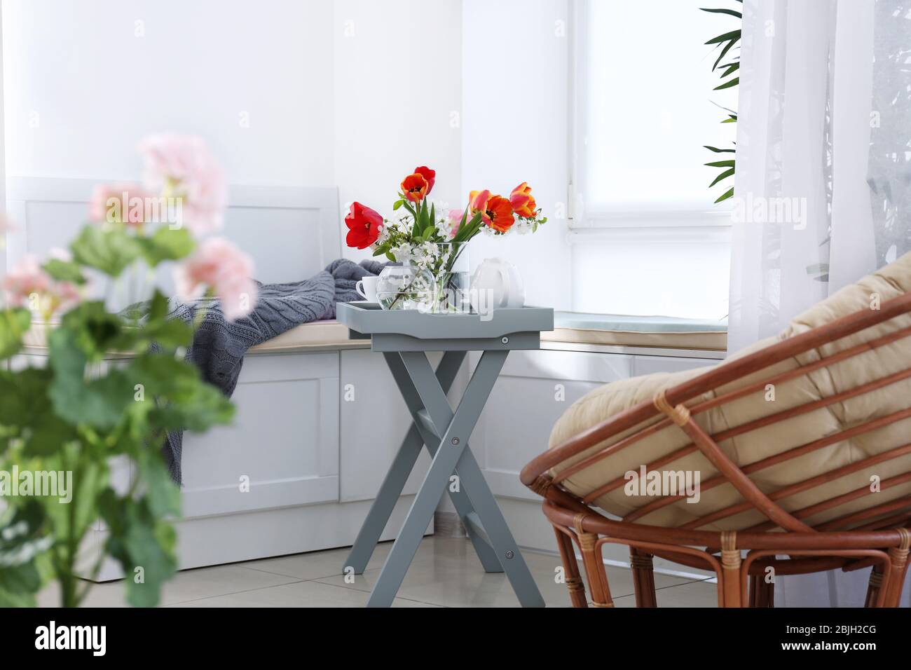 Vase with beautiful flowers and tea set on table in modern veranda ...