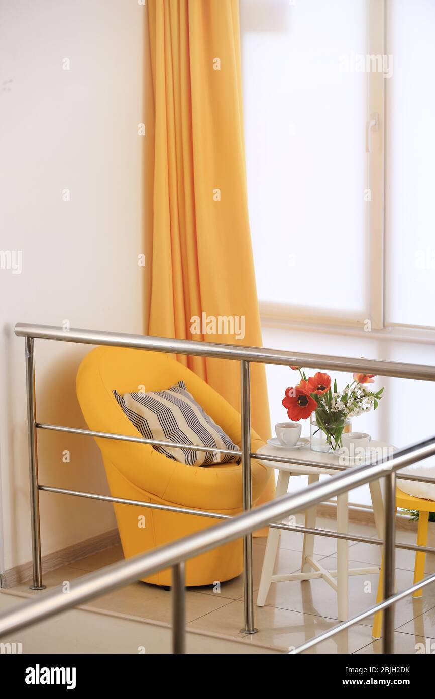 Vase with beautiful flowers and tea set on table in modern veranda ...