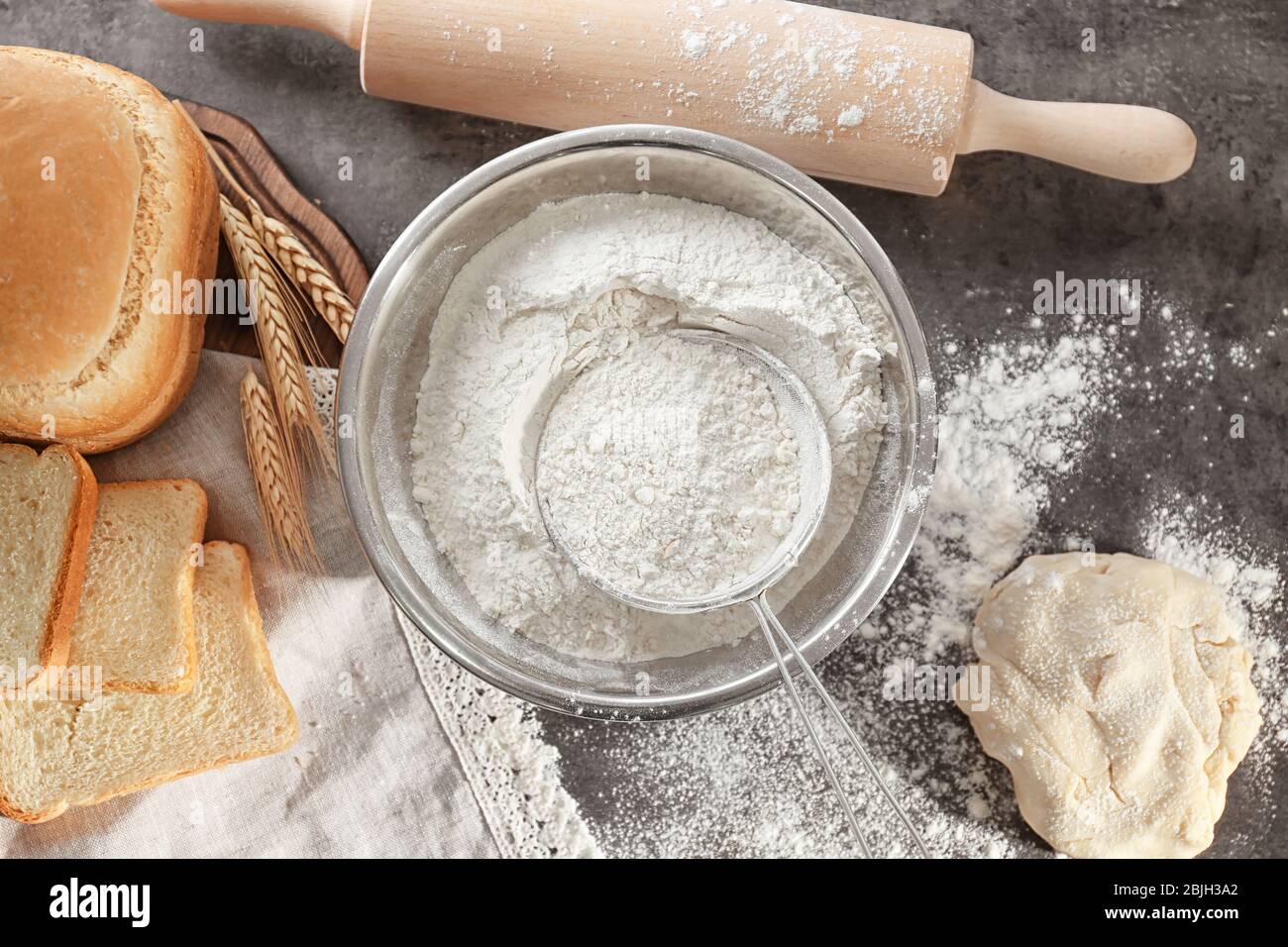 Sieve and bowl with flour on dark background, top view Stock Photo - Alamy