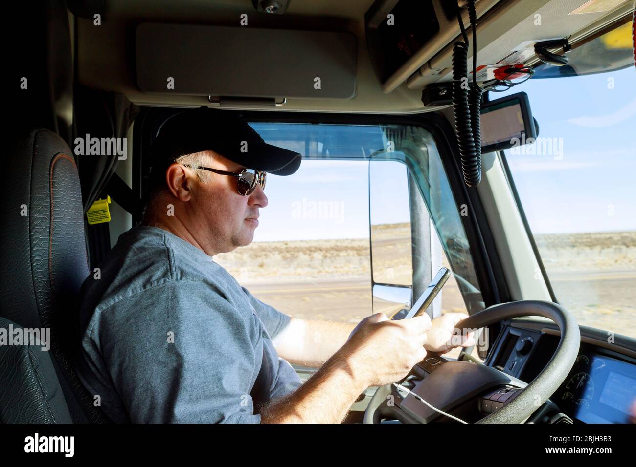Truck drivers big truck driver holds the phone in cabin of modern truck ...