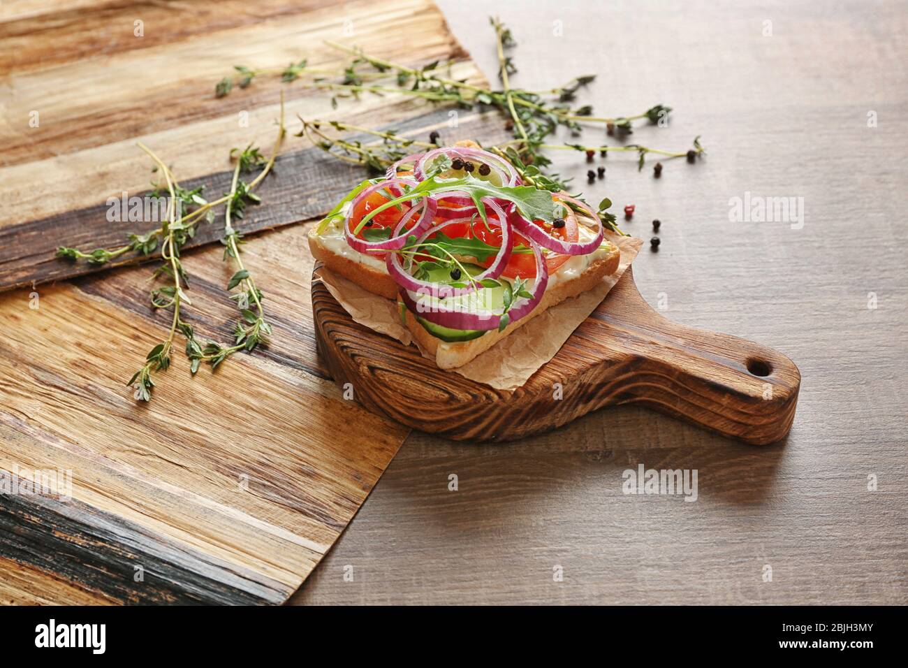 Wooden board with delicious toast and vegetables on table Stock Photo ...