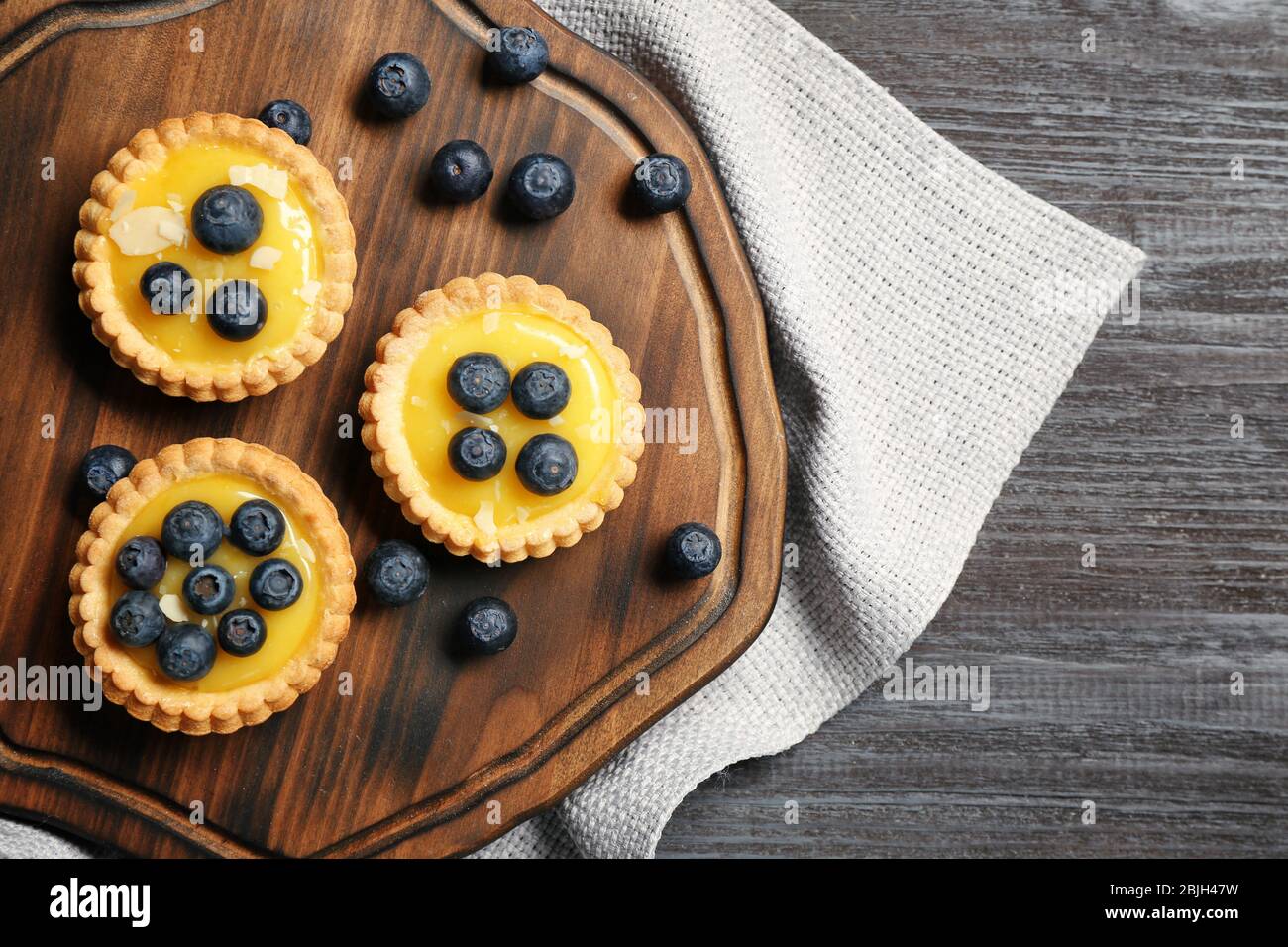 Delicious crispy tarts with blueberries and custard cream on wooden ...