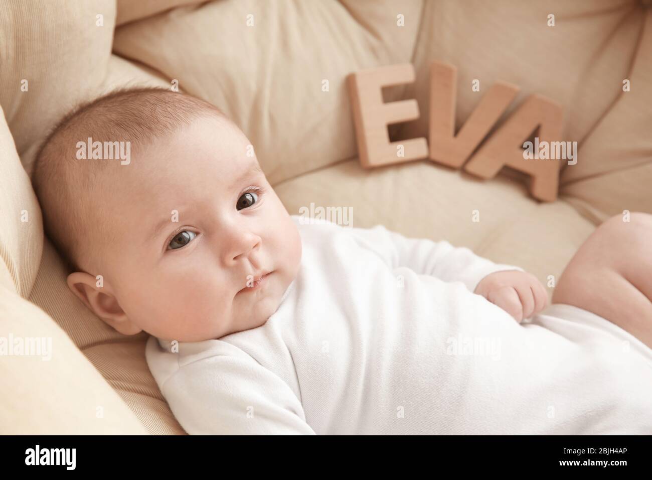 Cute baby with word EVA lying in armchair. Choosing name concept Stock ...