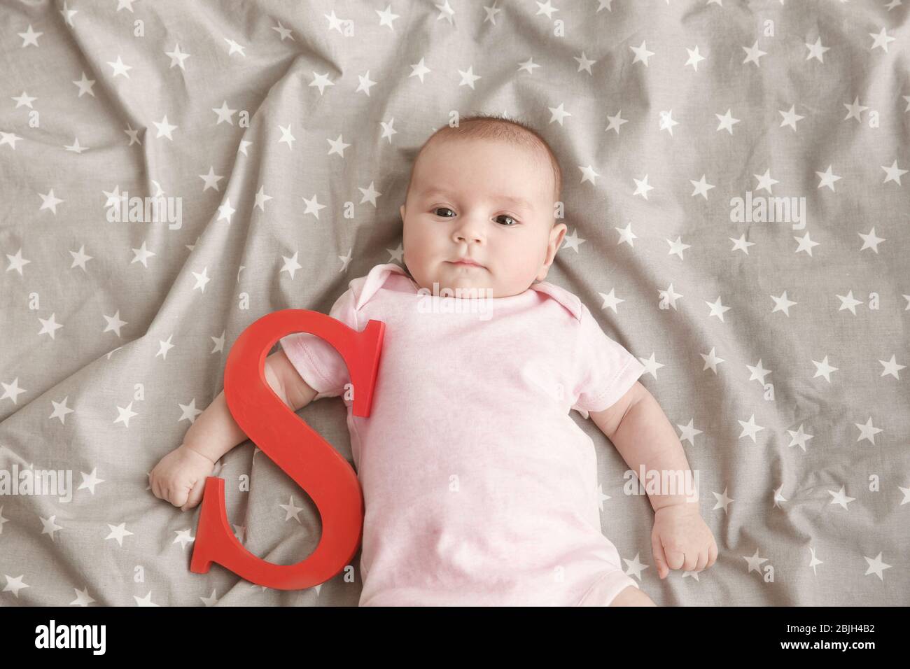 Cute baby with letter S lying on bed. Choosing name concept Stock Photo ...