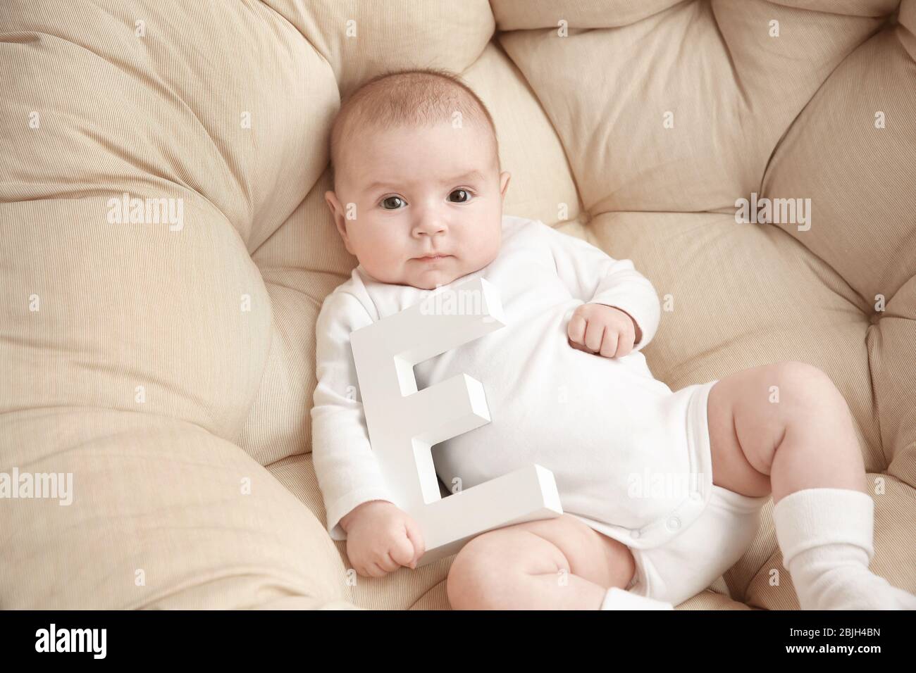 Cute baby with letter E lying in armchair. Choosing name concept Stock ...