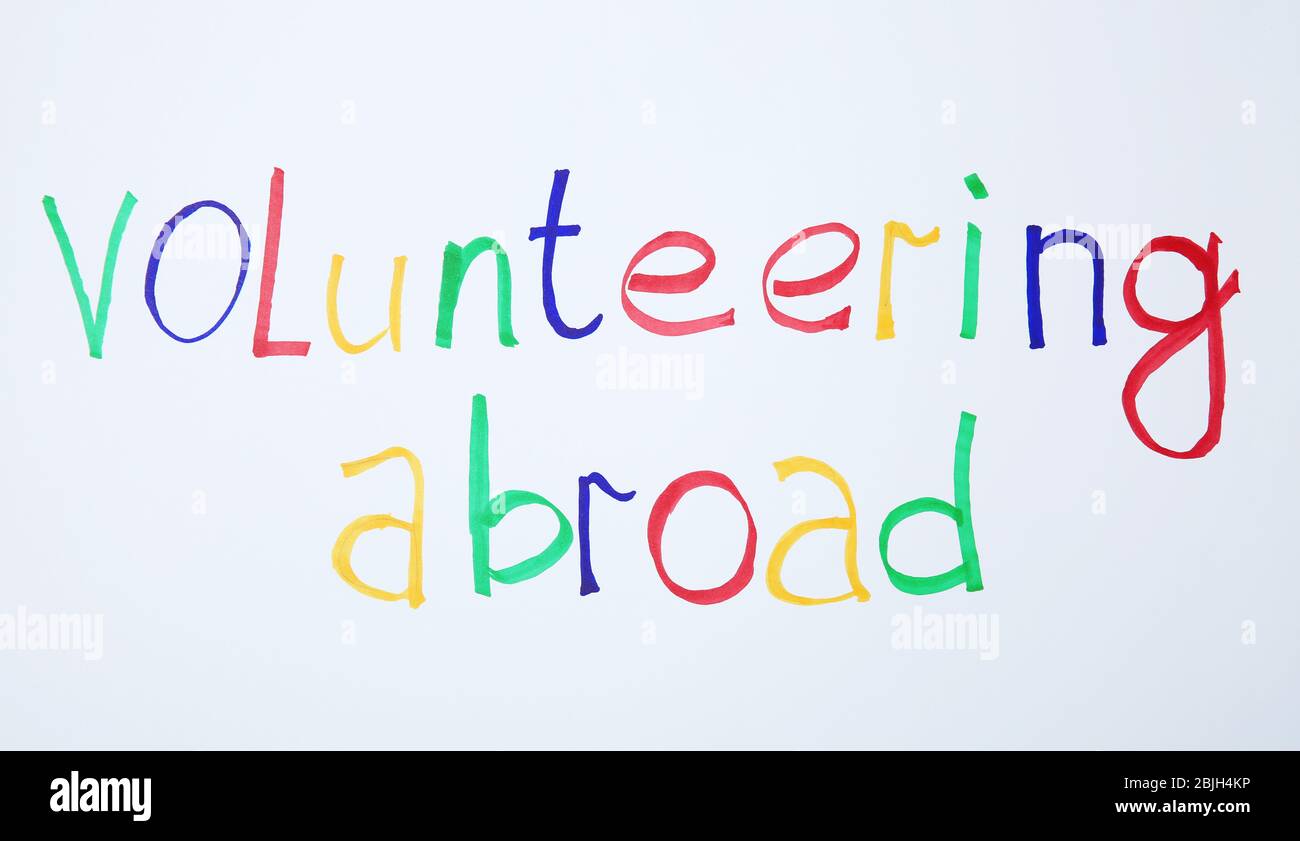 Text VOLUNTEERING ABROAD on white background Stock Photo - Alamy