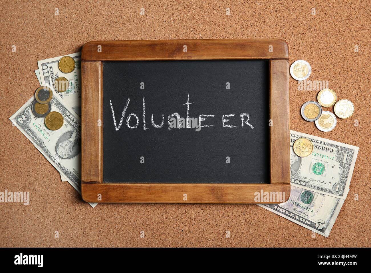 Little chalkboard with word VOLUNTEER and money on cork background ...