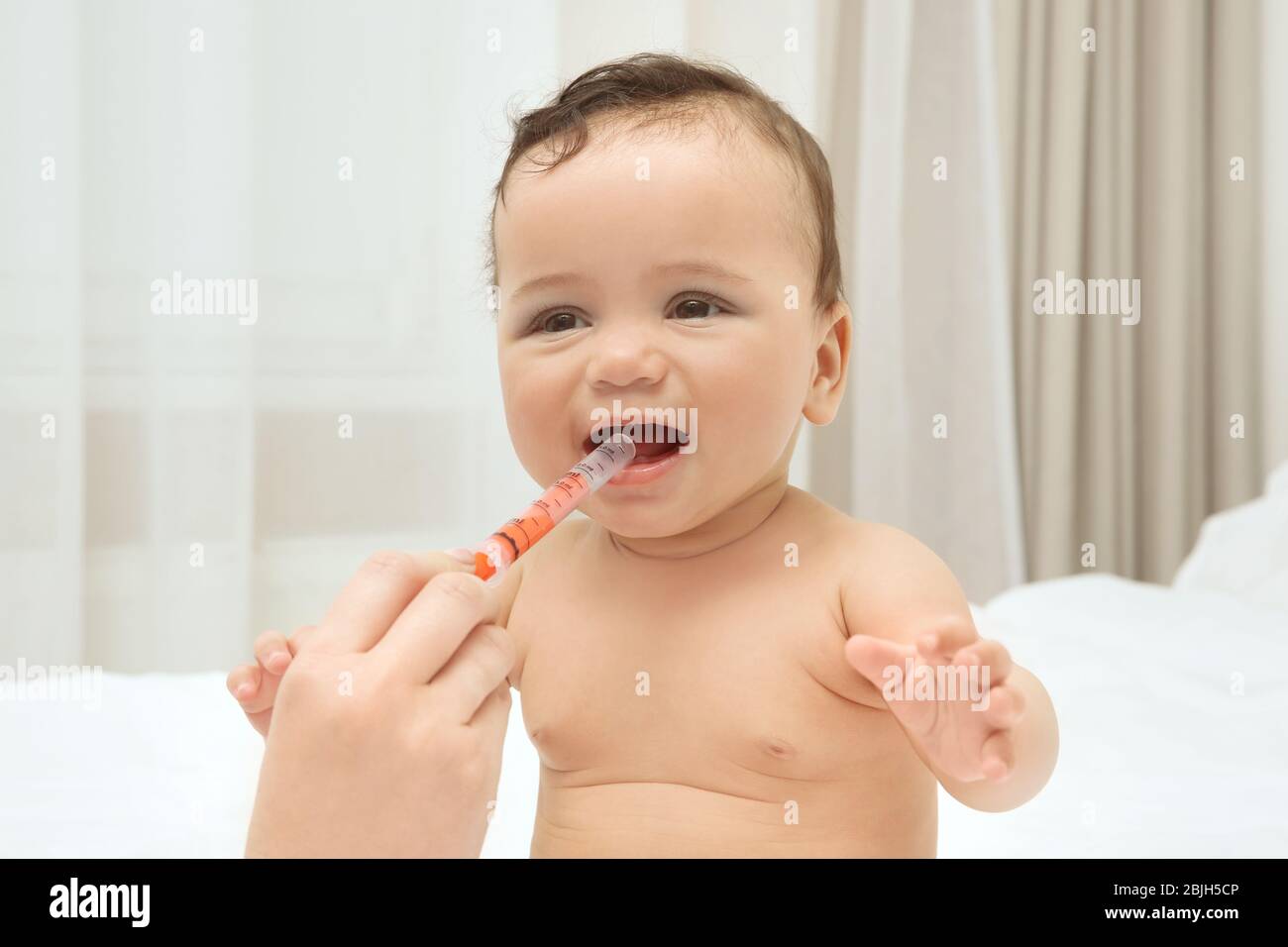Mother using special syringe to give medicine to her child at home ...