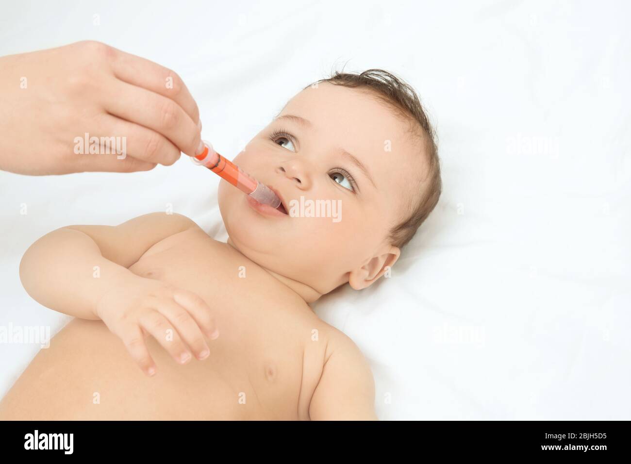 Mother using special syringe to give medicine to her child at home ...