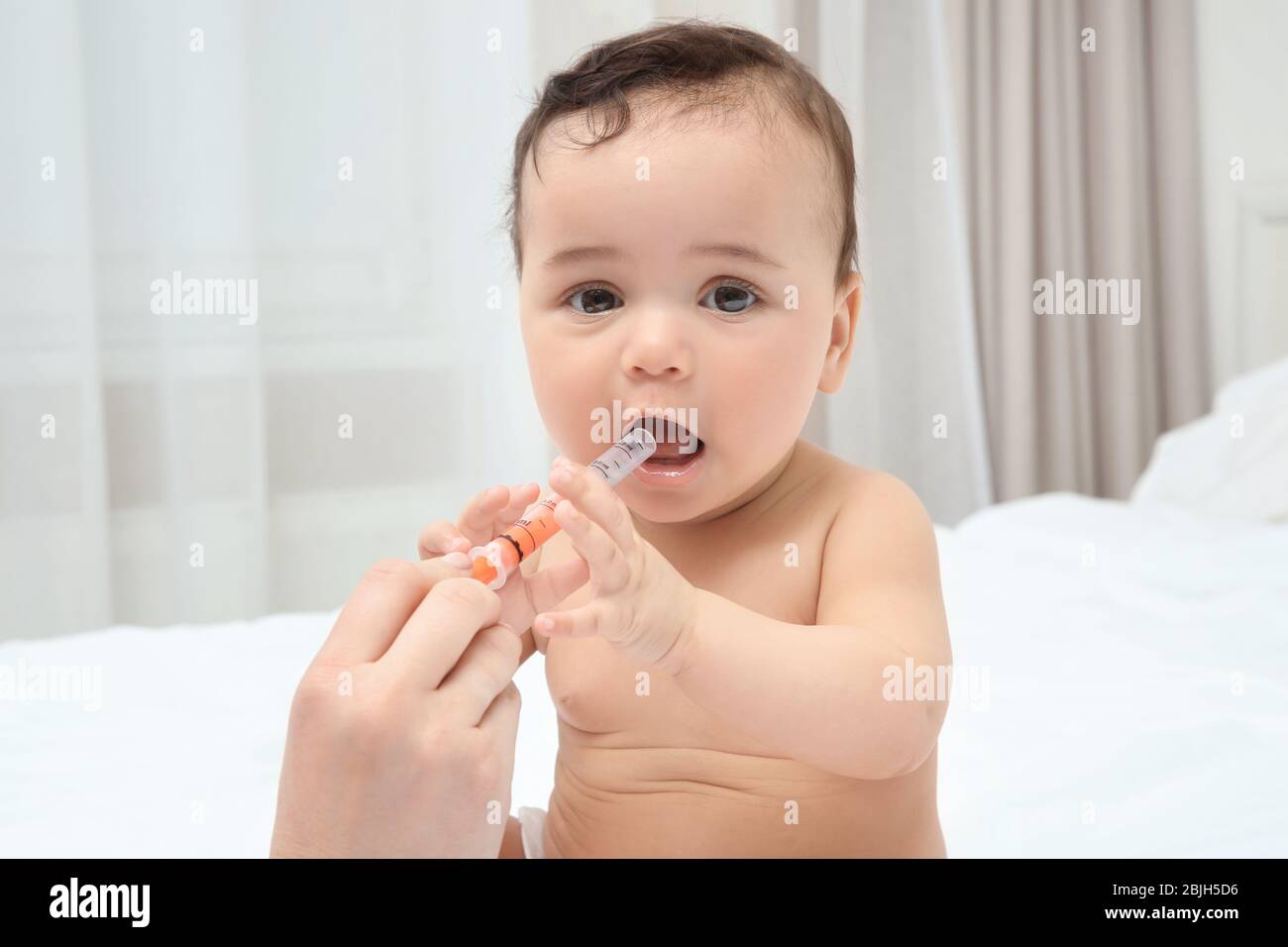 Mother using special syringe to give medicine to her child at home ...
