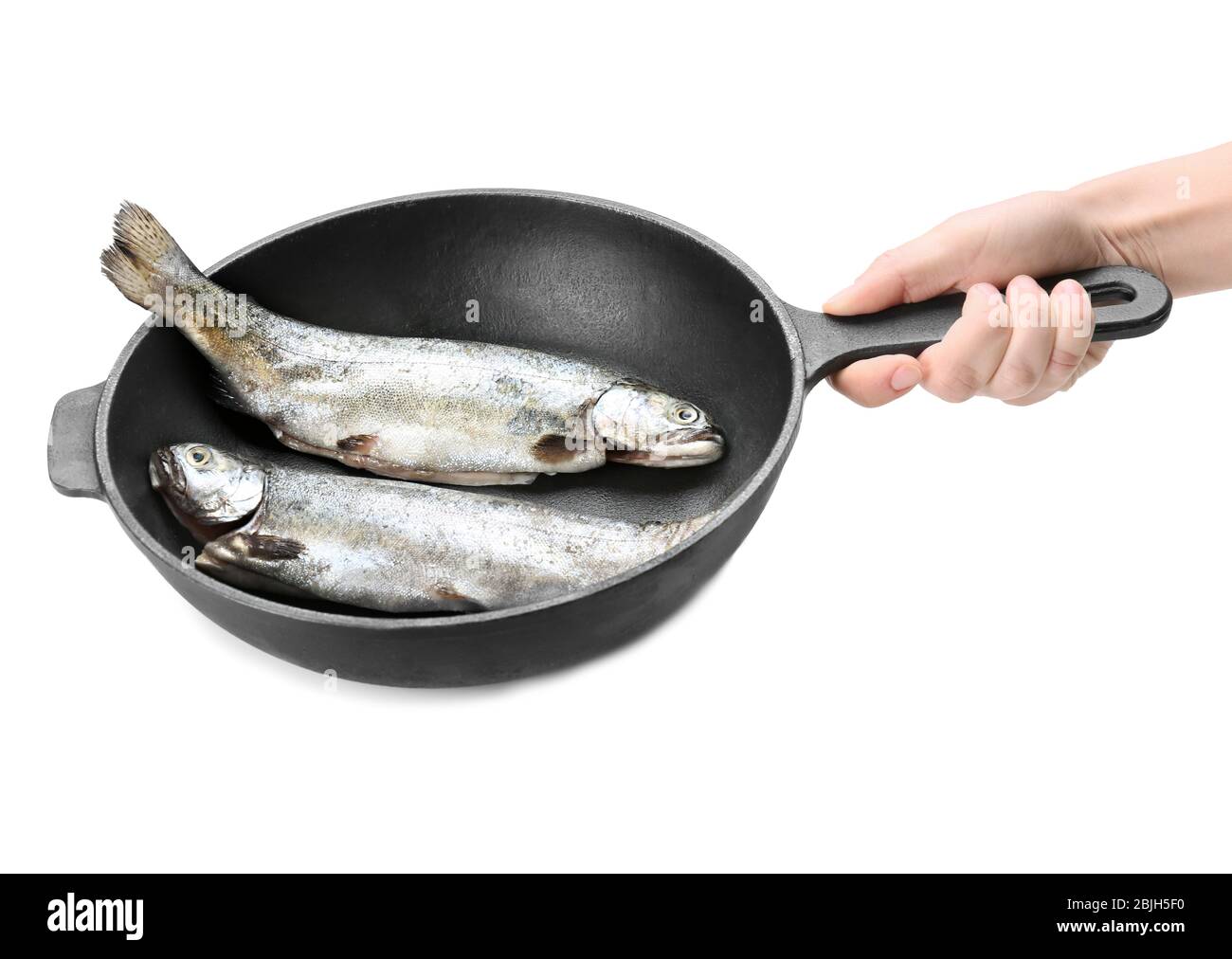 Female hand holding frying pan with fresh trout fish on white ...