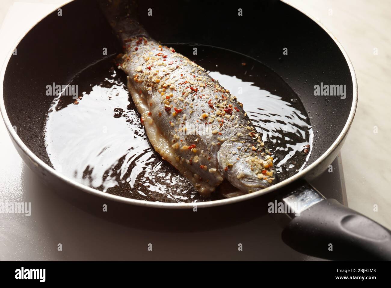 Cooking trout fish on frying pan, closeup Stock Photo - Alamy
