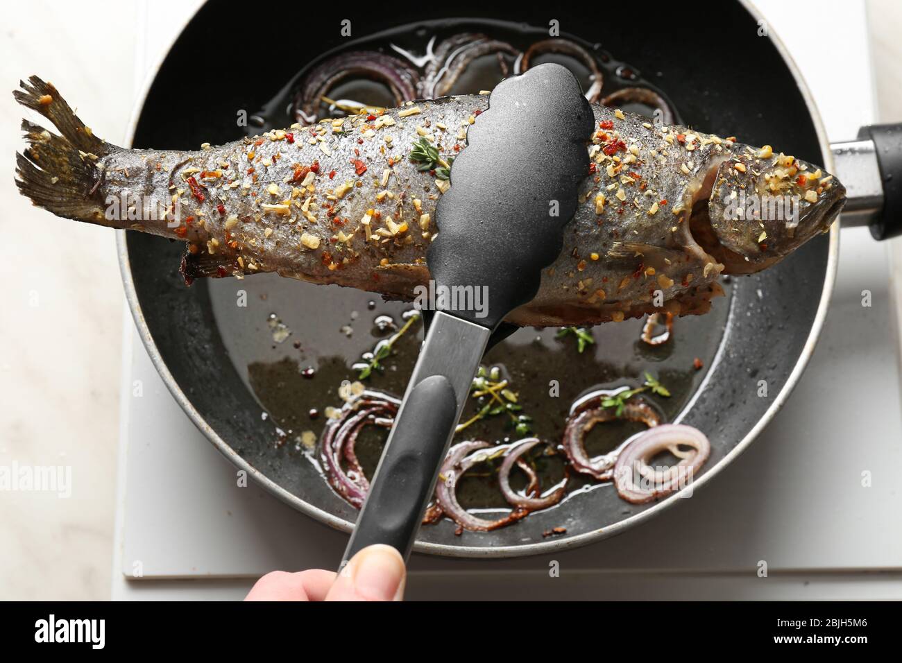 Hand holding cooking tongs hi-res stock photography and images - Alamy