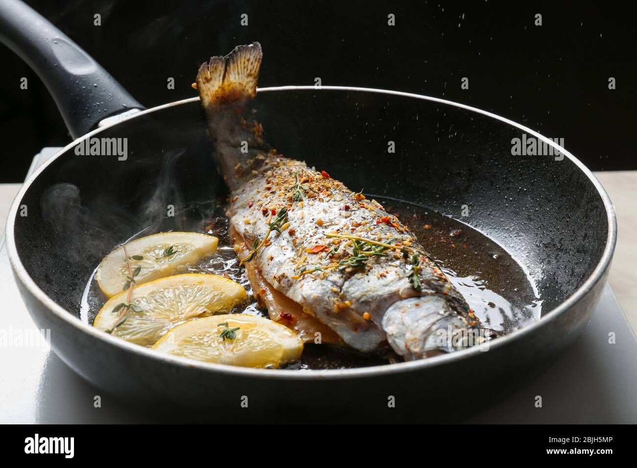 Cooking trout fish on frying pan, closeup Stock Photo - Alamy