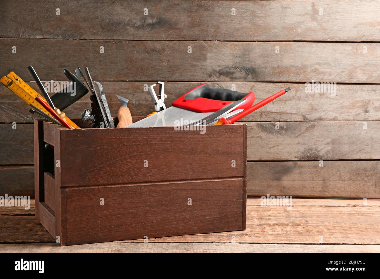 Box with carpenter's tools on table against wooden background Stock ...