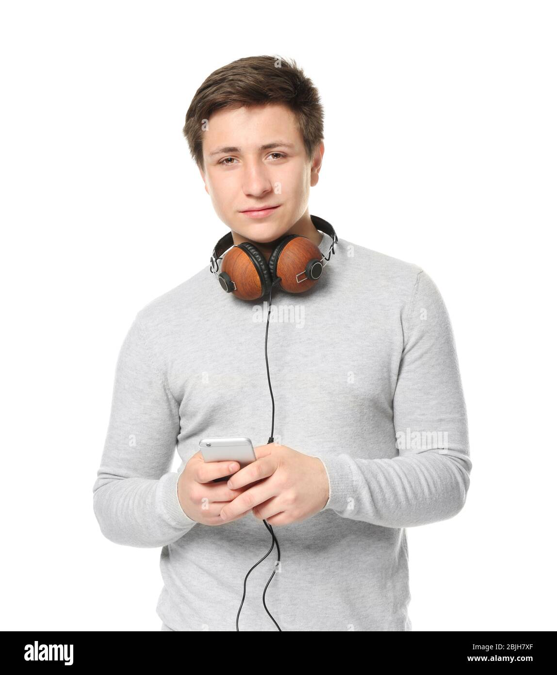 Cute teenage boy with mobile phone and headphones on white background ...