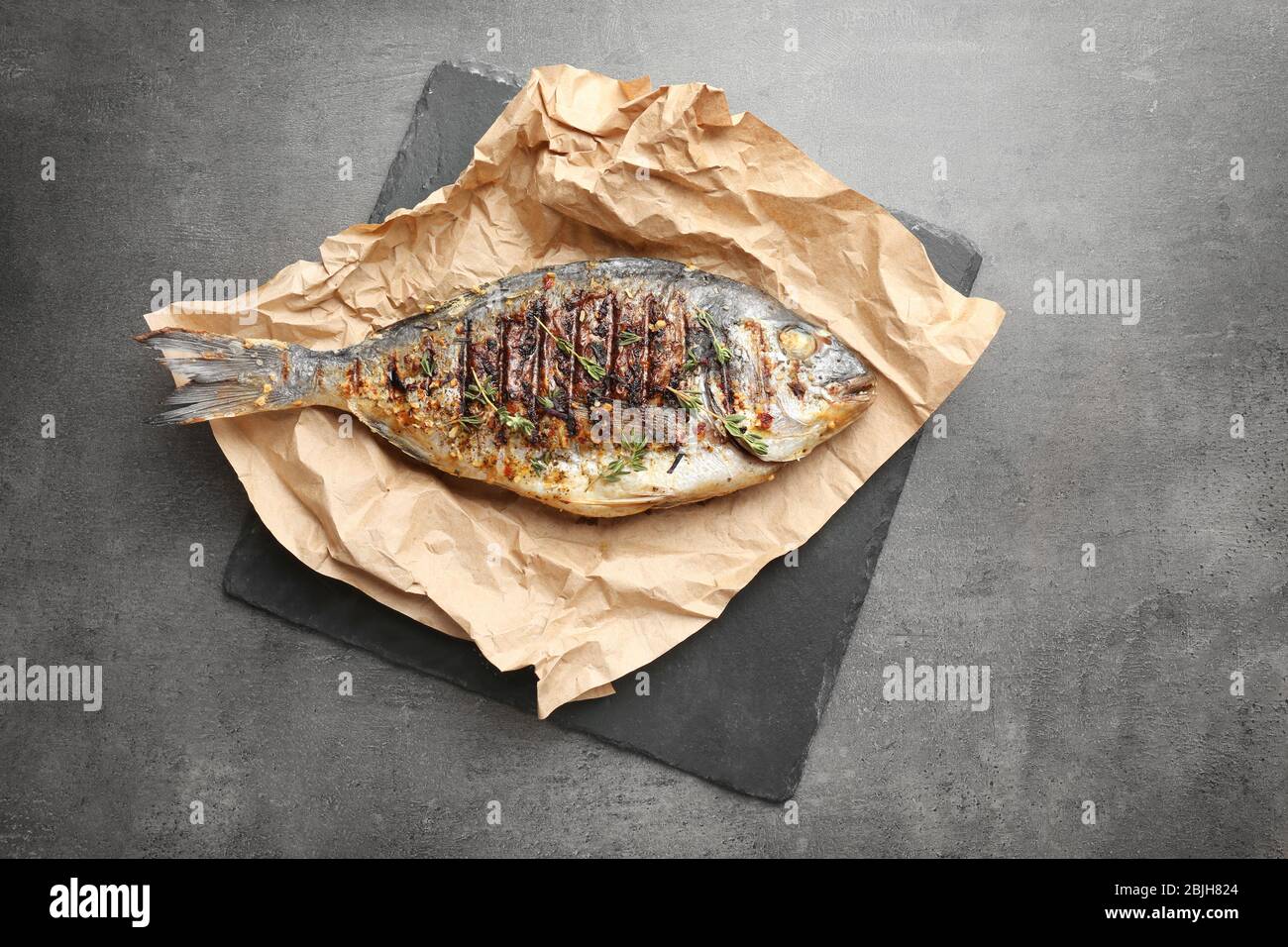 Paper with delicious fried fish on table Stock Photo - Alamy