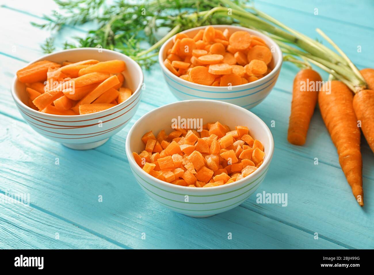 Different cuts of carrot in bowls on wooden background Stock Photo - Alamy