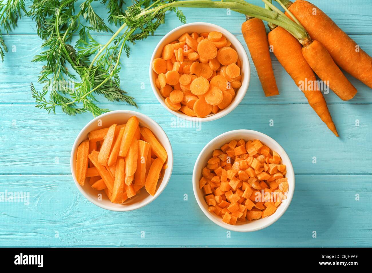 Different cuts of carrot in bowls on wooden background Stock Photo - Alamy