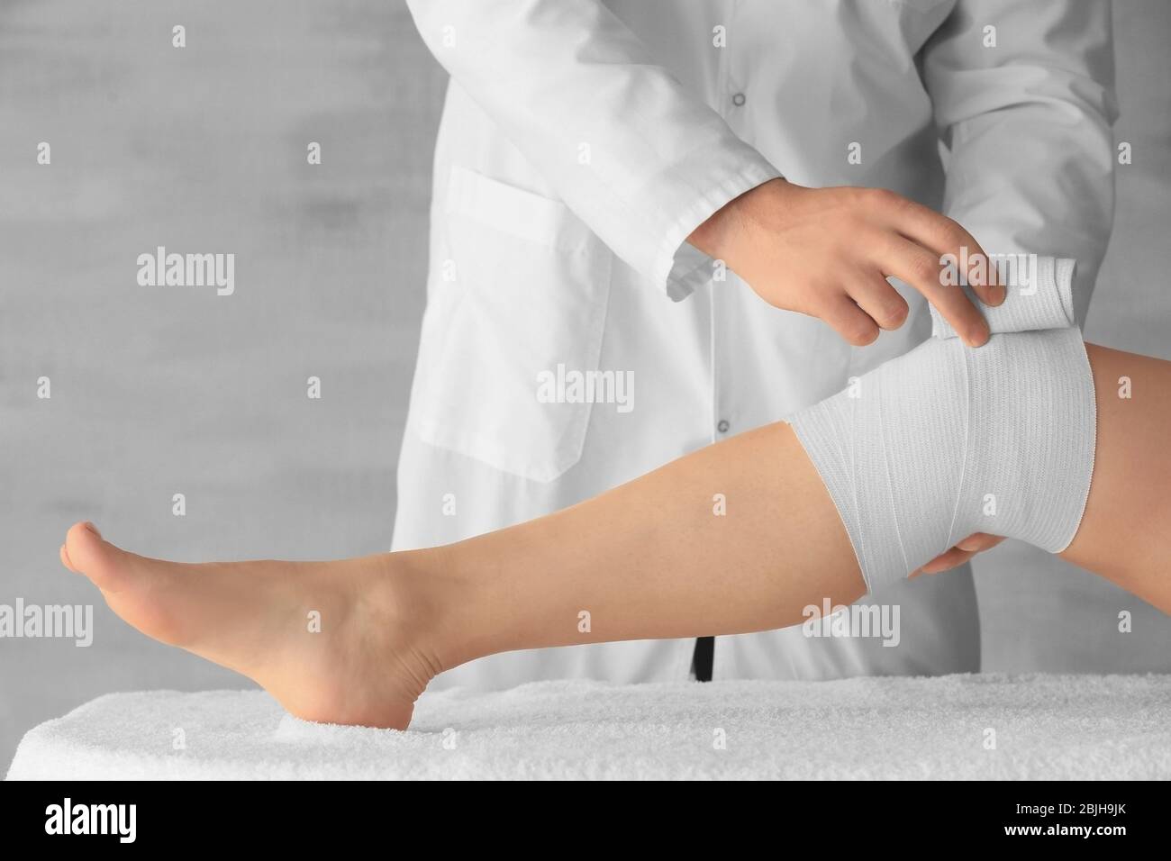 Doctor applying bandage onto patient's leg in clinic Stock Photo - Alamy
