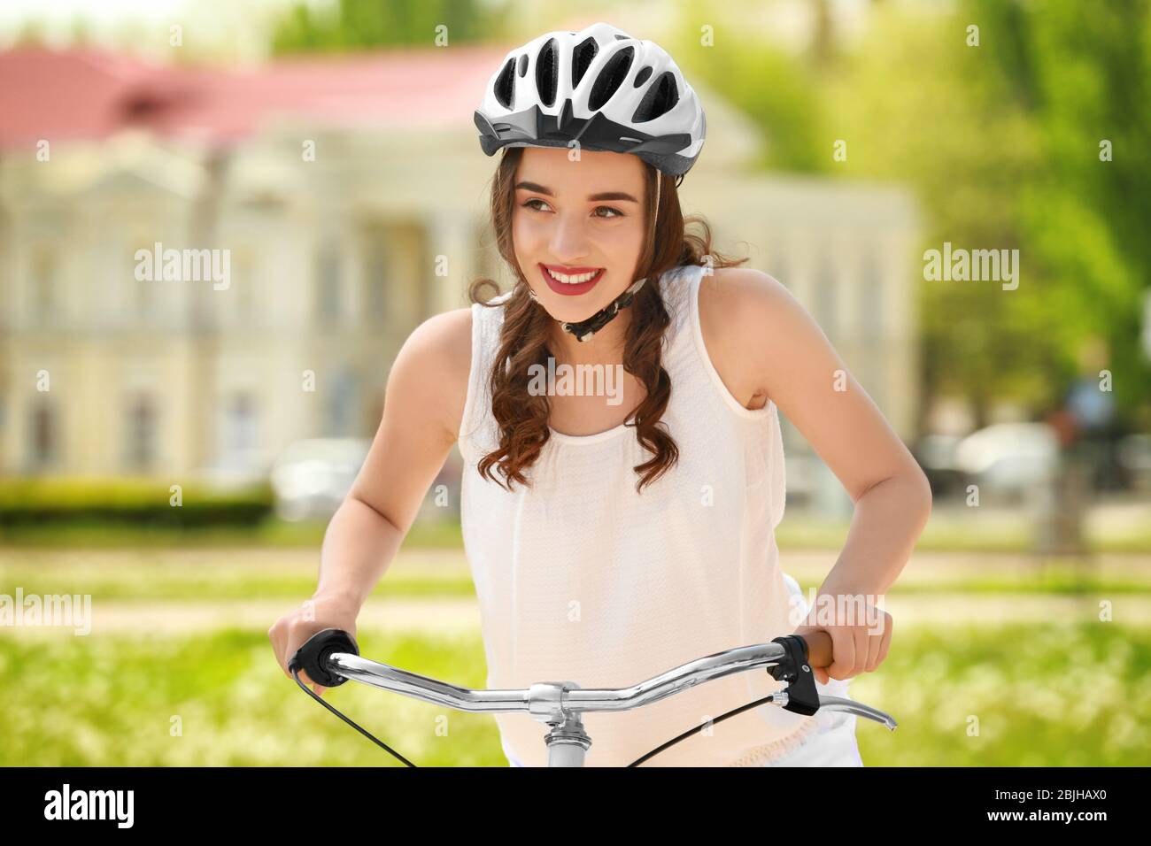 Beautiful young woman riding bicycle in park on sunny day Stock Photo - Alamy