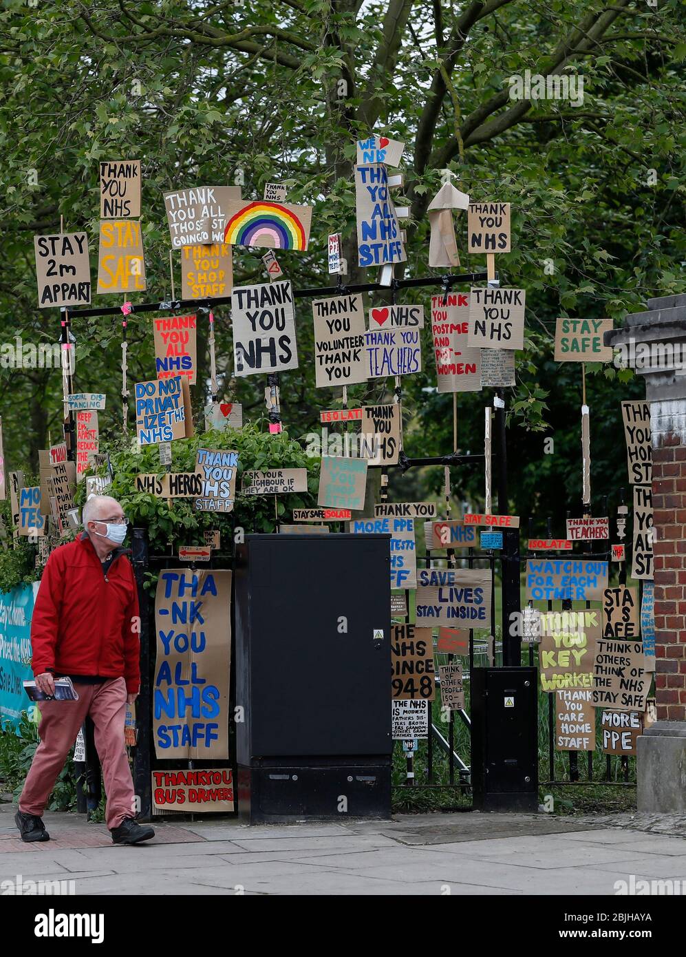 London, Britain. 29th Apr, 2020. A man walks past a display of signs ...