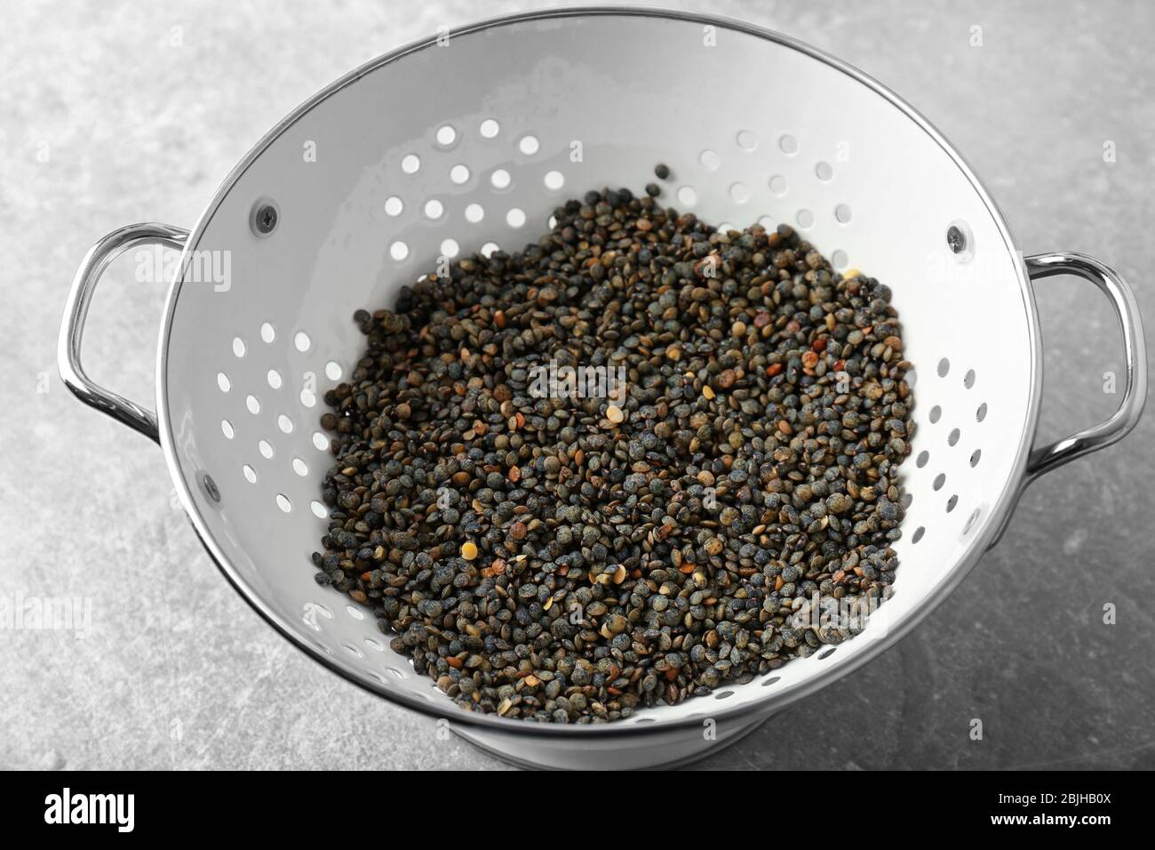 Collander with raw lentils on table, closeup Stock Photo - Alamy