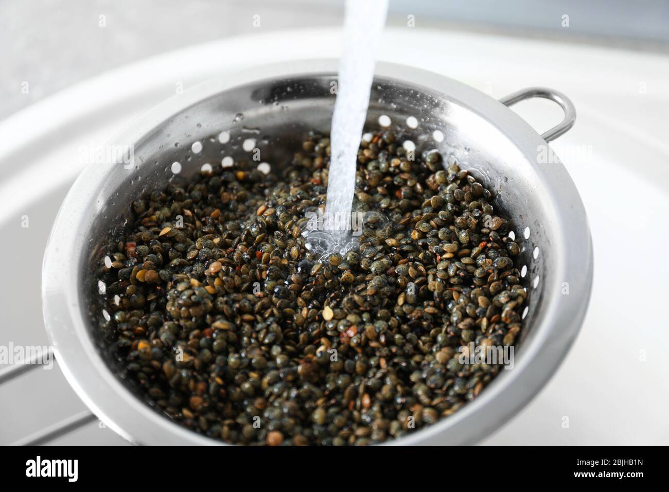 Washing raw lentils with tap water before cooking, closeup Stock Photo ...