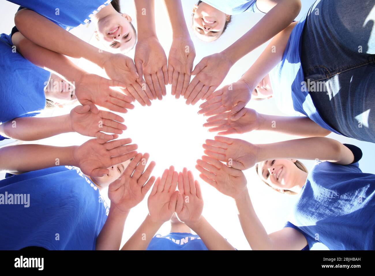 Team of volunteers putting their hands together as symbol of unity ...