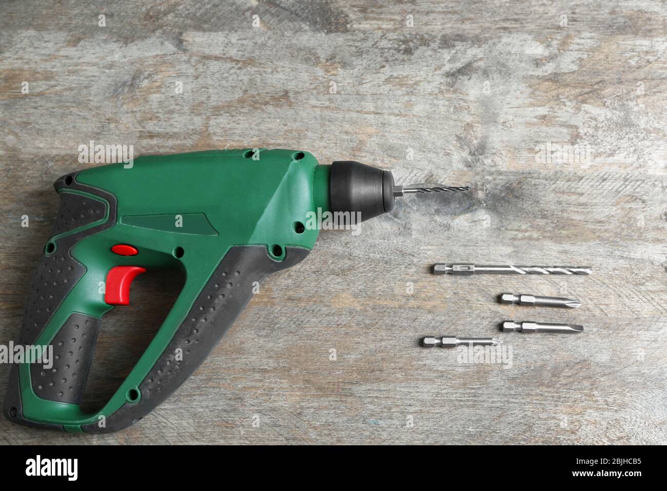 Modern drill with attachments on wooden table in carpenter's workshop ...