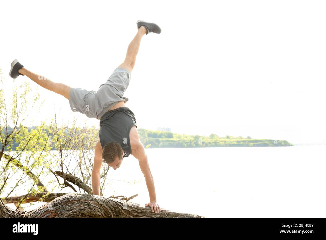 Young sporty man doing acrobatic exercises near river Stock Photo - Alamy