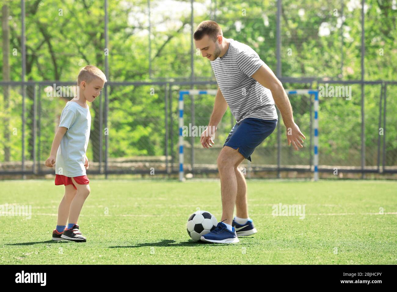 Father and son playing football on soccer pitch Stock Photo - Alamy