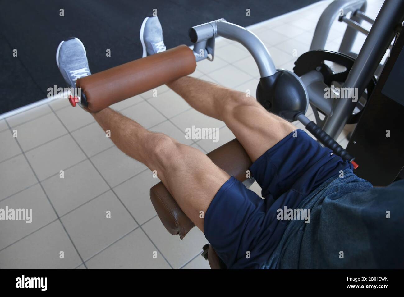 Sporty young man training legs in gym, closeup Stock Photo - Alamy